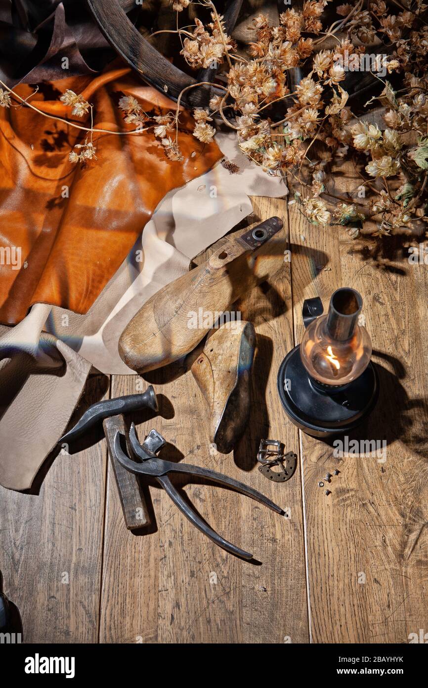 Shoes, shoemaking tools and pieces of leather on a studio background ...