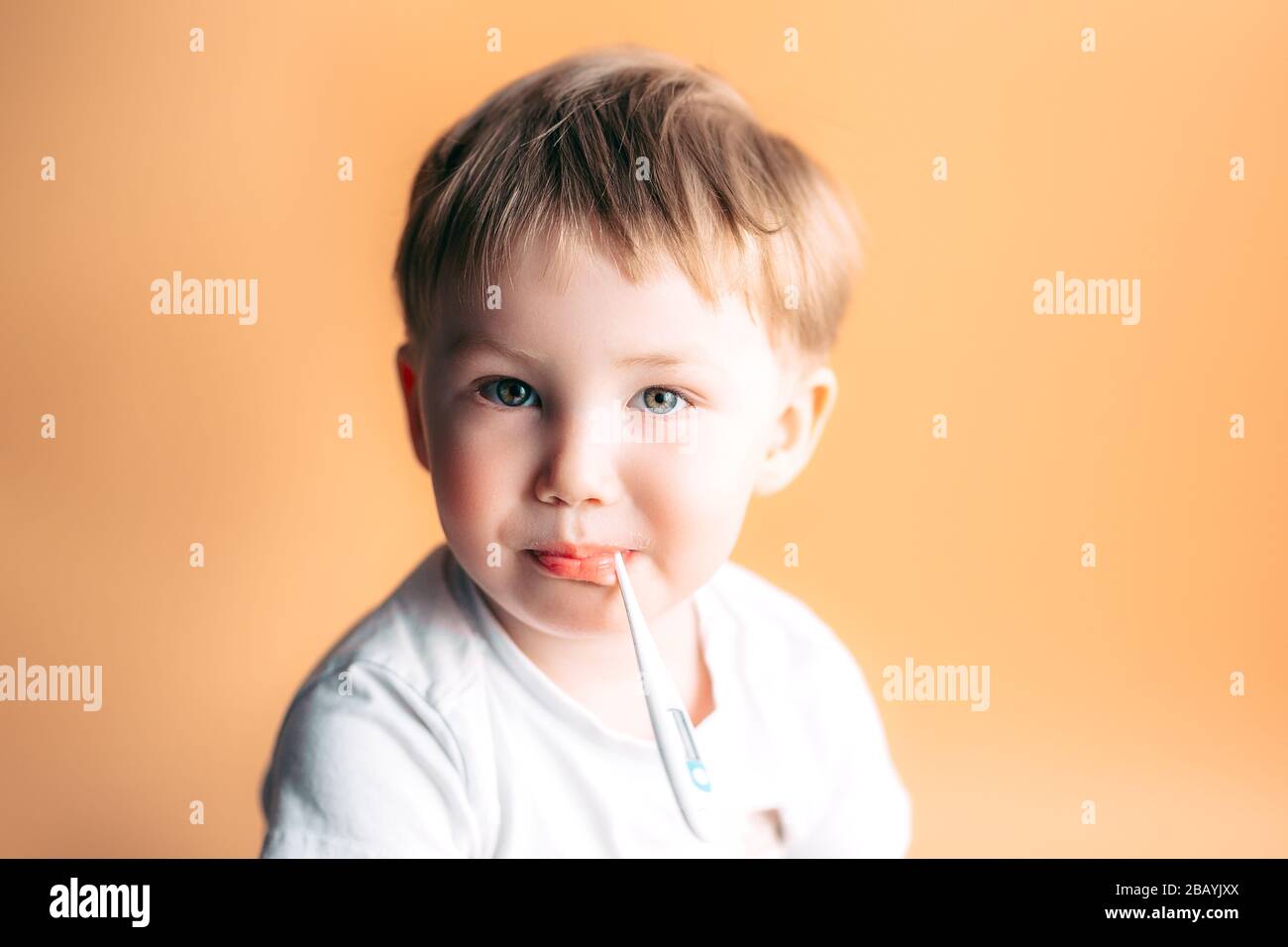 Sick kid with a thermometer in his mouth with sad face on orange ...