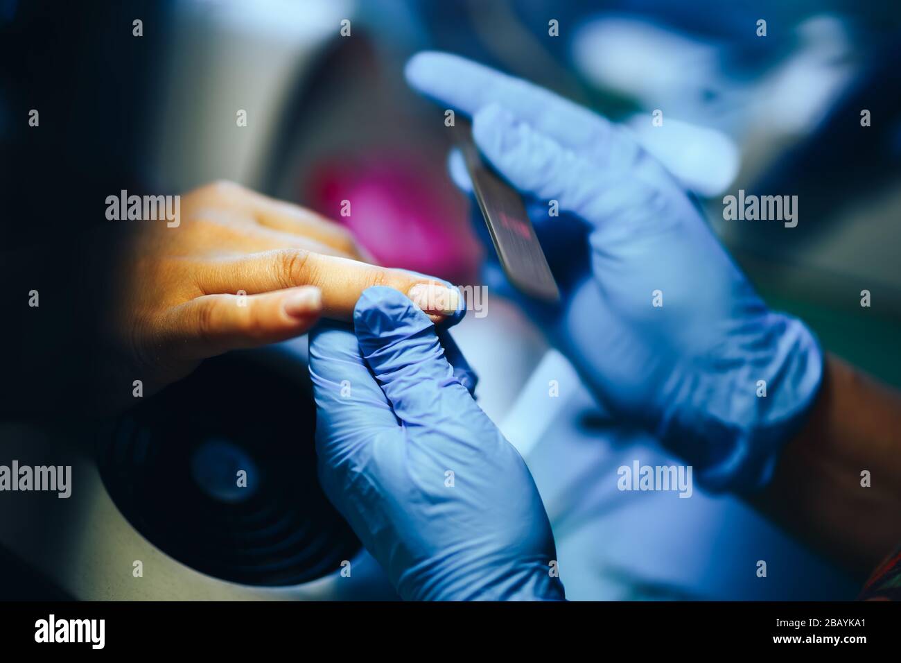 Manicurist master make manicure in blue gloves with nail file. Woman ...