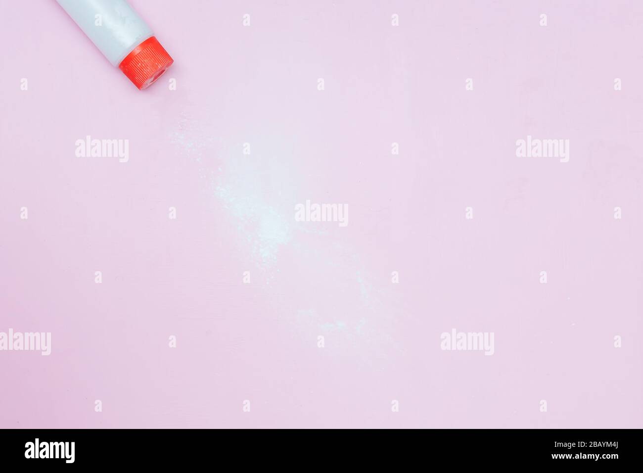 Bottle of Talcum baby powder on pink background. Powder spilled from ...