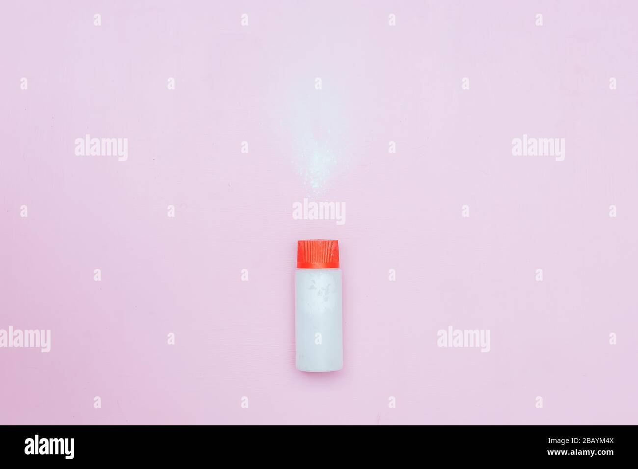 Bottle of Talcum baby powder on pink background. Powder spilled from ...