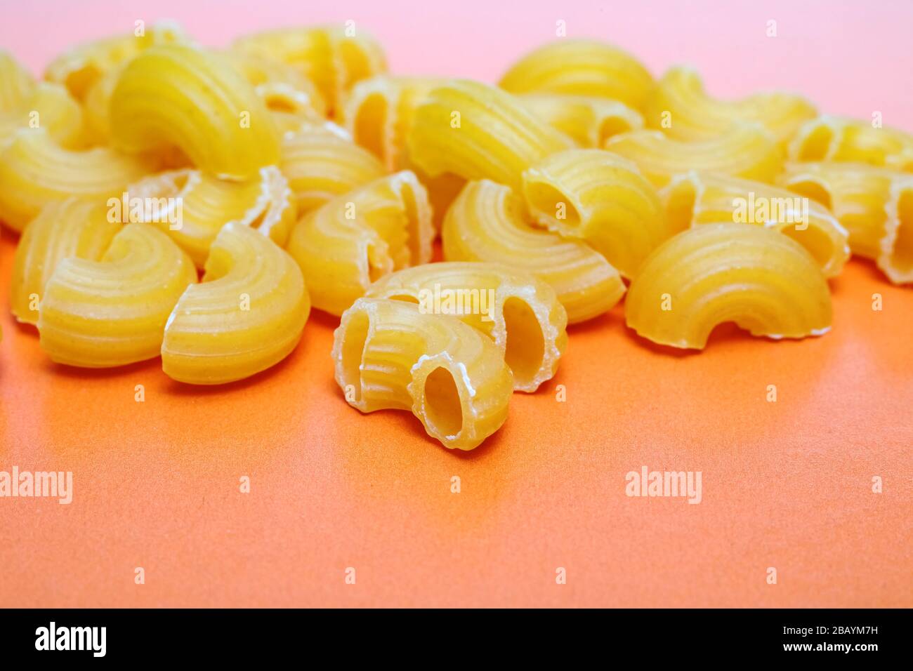 Yellow pasta isolated on a red background closeup Stock Photo - Alamy