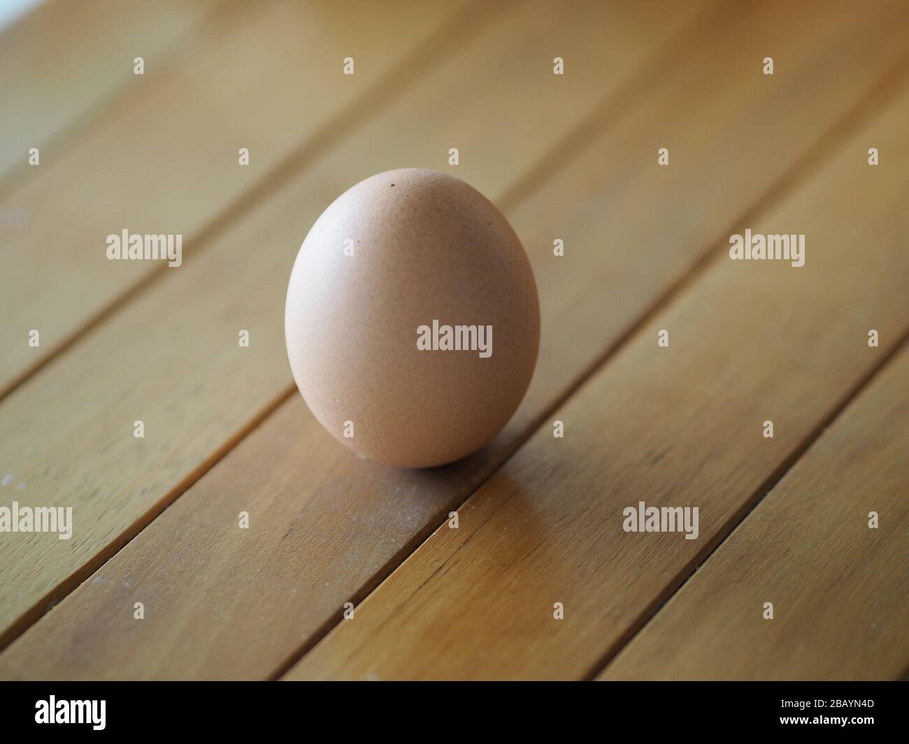Fresh egg on brown wooden desk Stock Photo - Alamy
