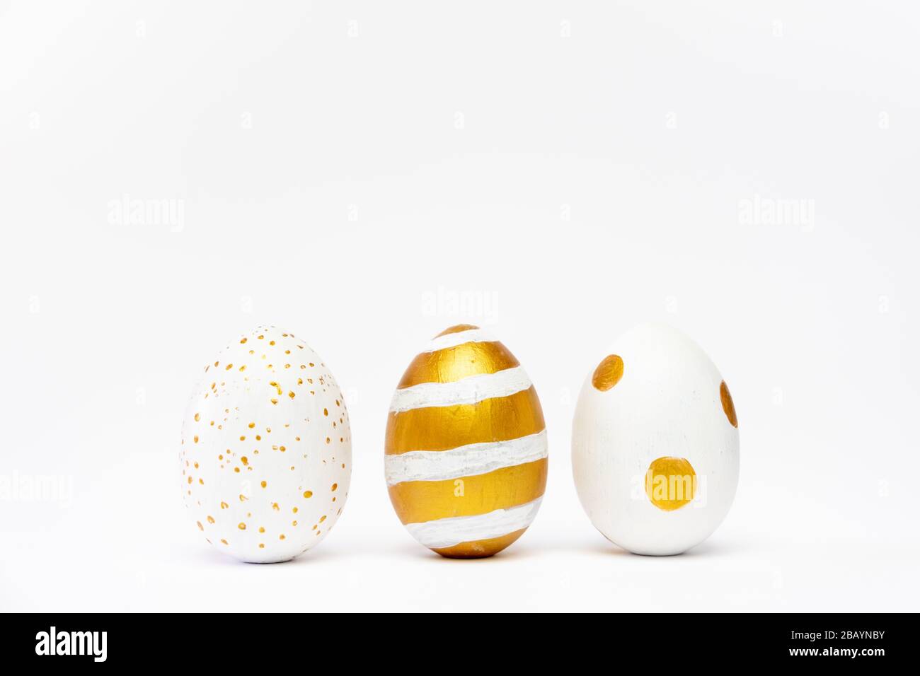 Three easter trendy golden decorated eggs on white background. Happy ...