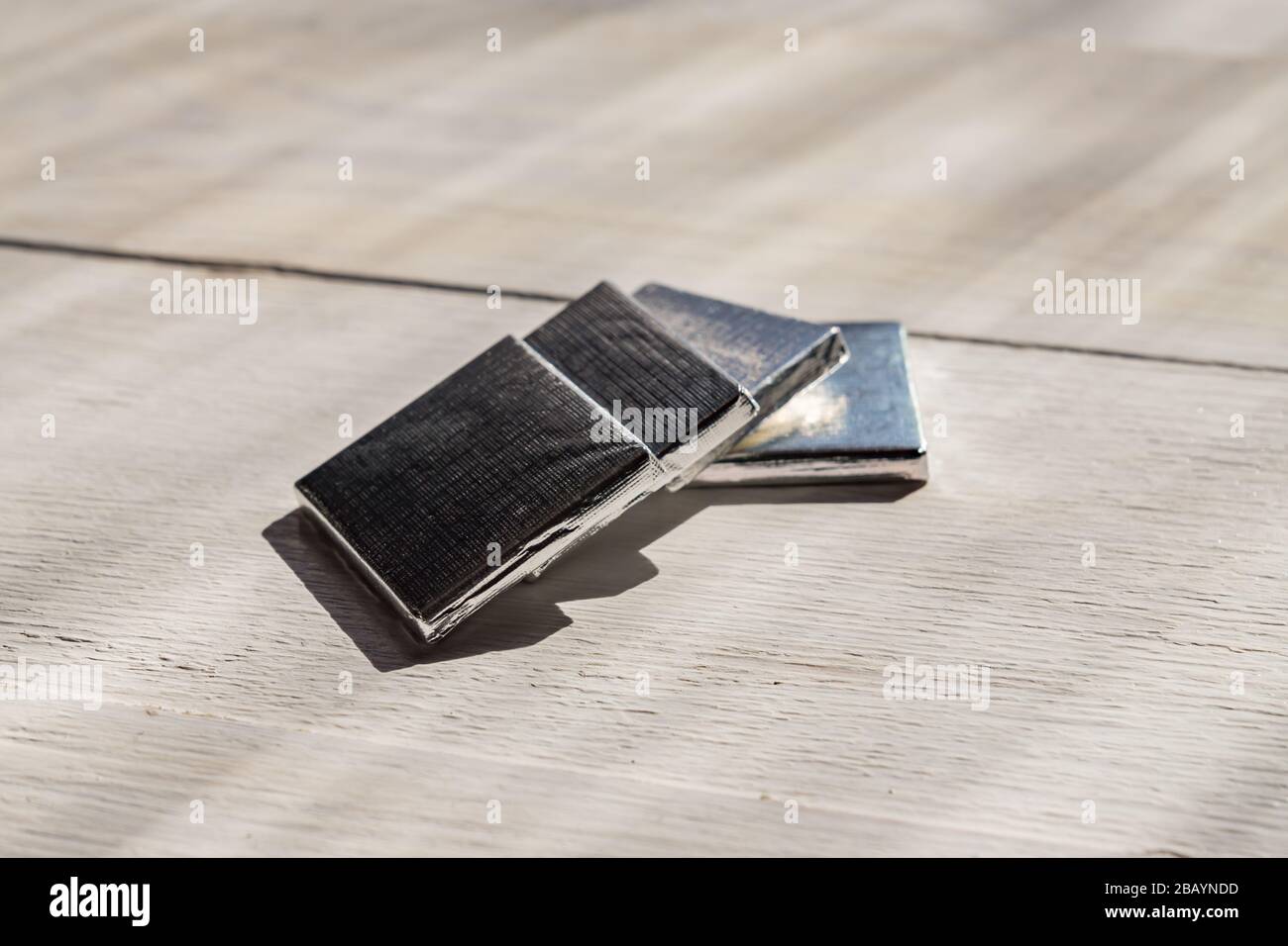 Mini chocolate bars in silver paper on white wooden background. Natural ...
