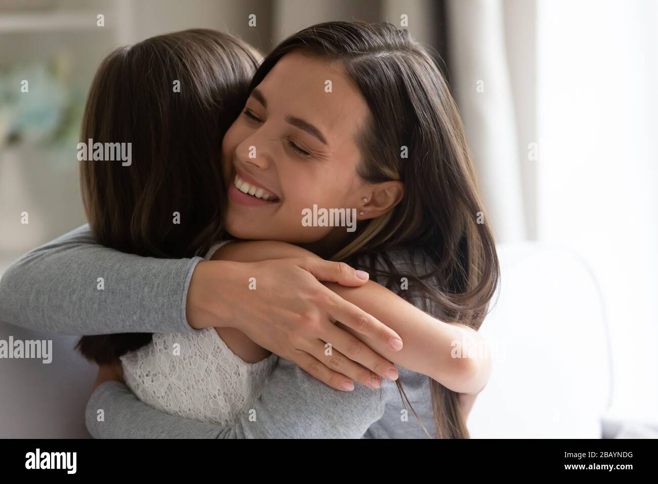 Smiling young mother and little daughter hug making peace Stock Photo ...