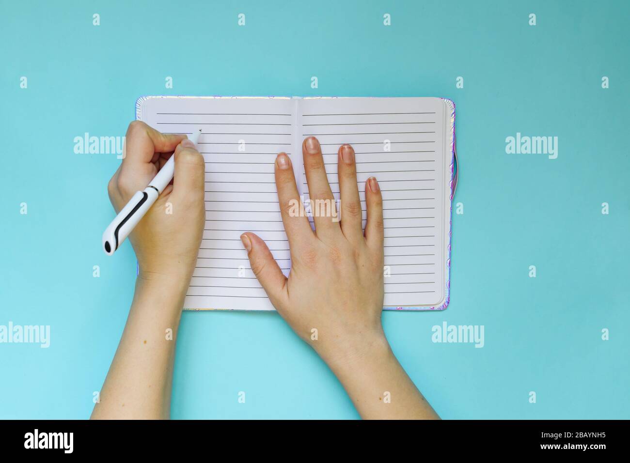 Left handed woman makes notes in her planning or dary on blue ...