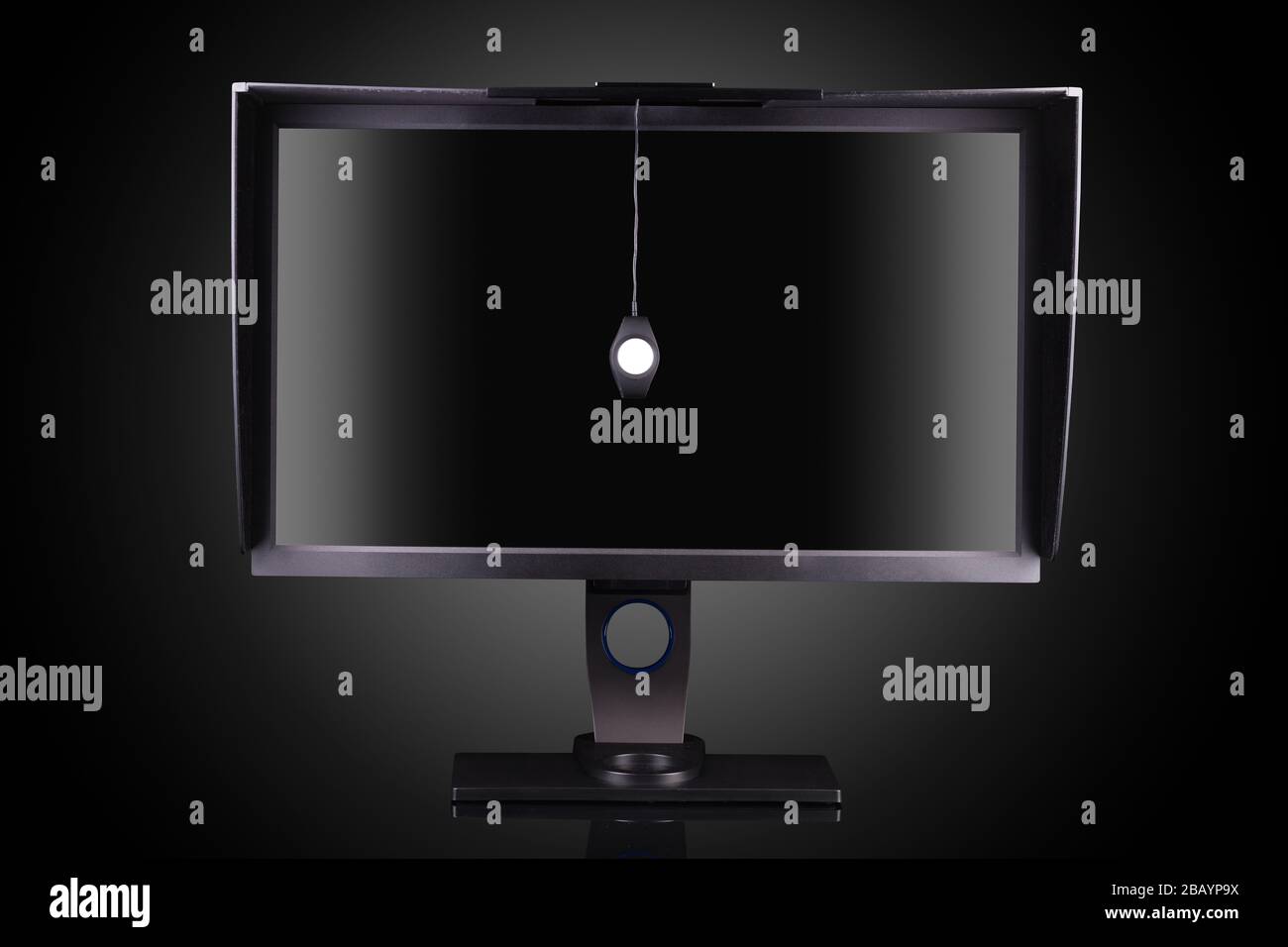 Professional monitor with shading hood and calibrator isolated on black ...