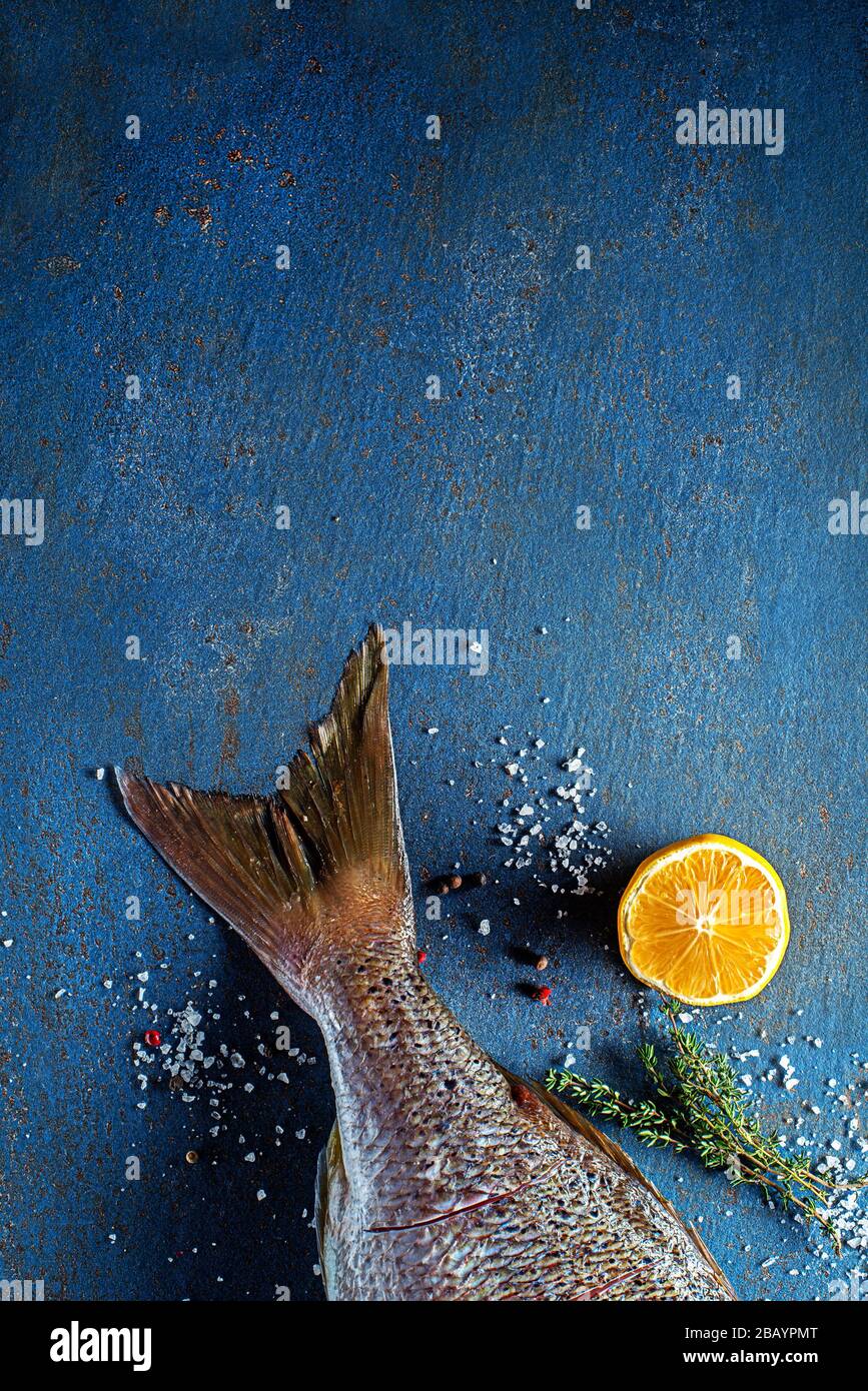 Delicious fresh fish tail with spices on vintage blue background ...