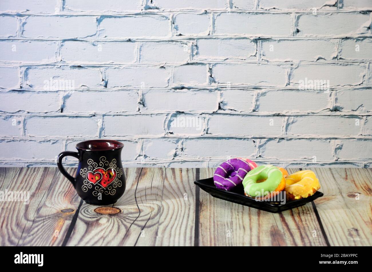 A rectangular plate with five multi-colored donuts and a black ceramic ...