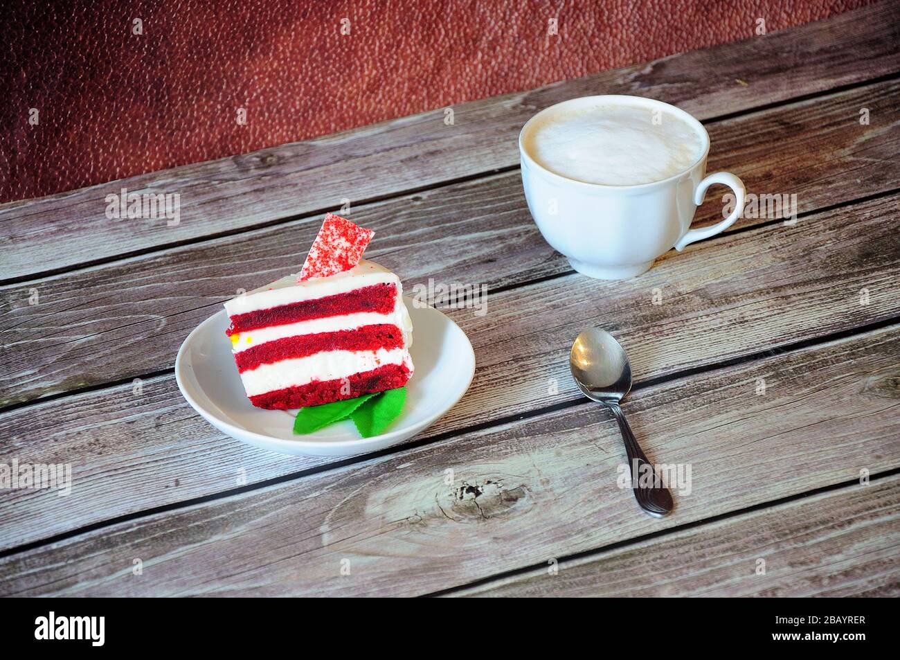 A piece of red velvet cheesecake and a cup of fresh cappuccino with a ...