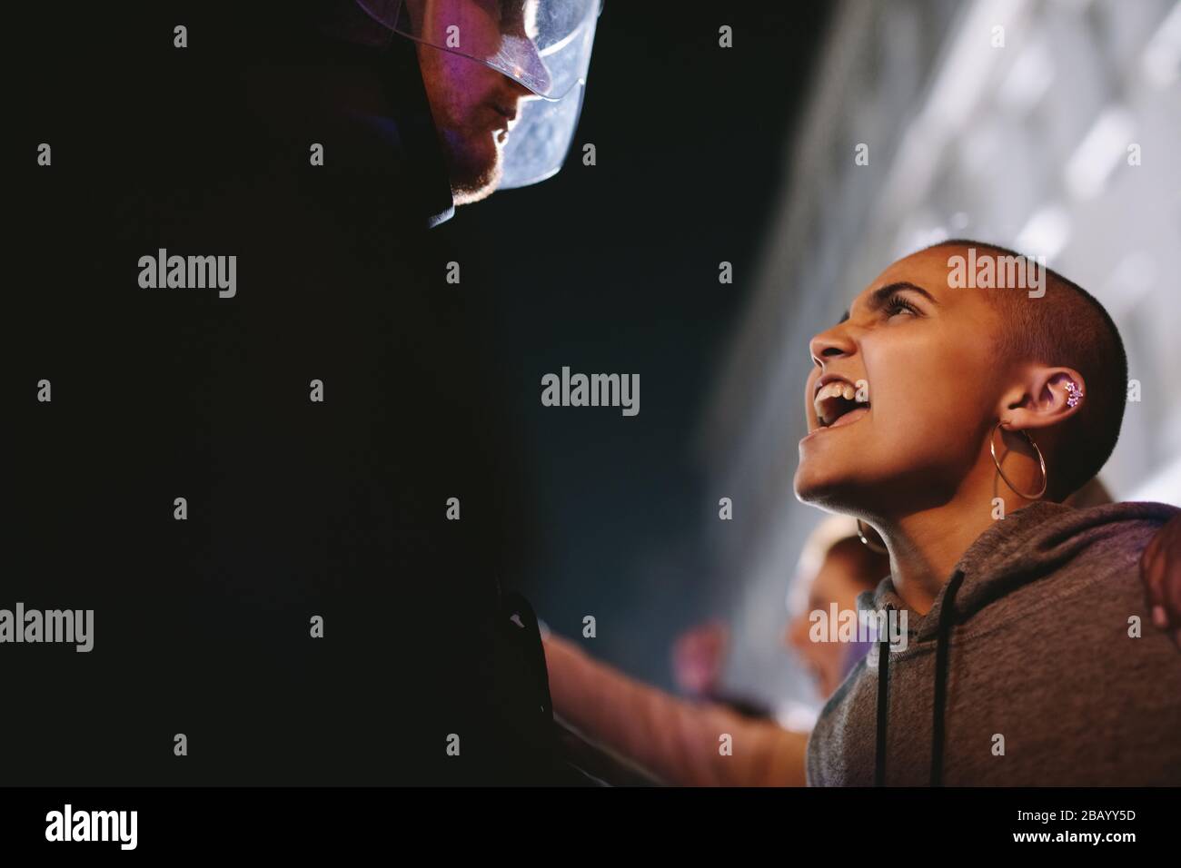 Angry female protestor giving slogans in front of police force. Woman ...