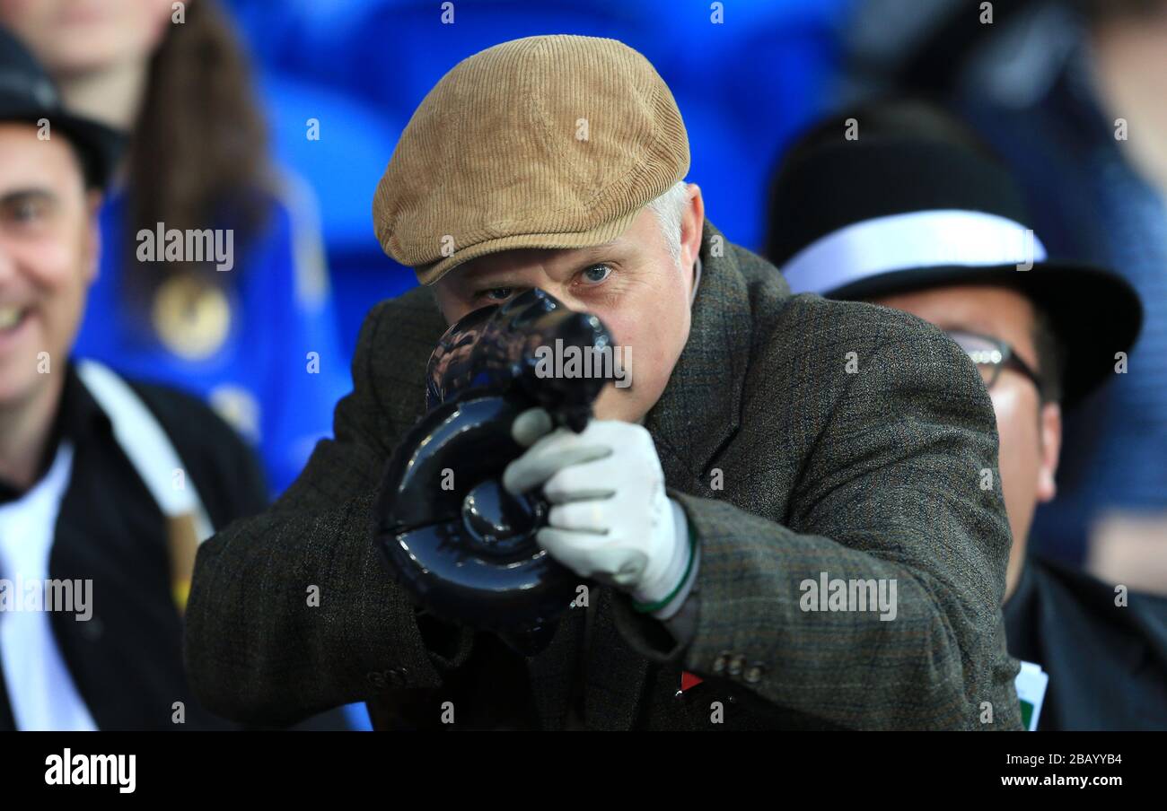 A fan wearing a flat cap and a inflatable 'Tommy Gun' in the stands ...