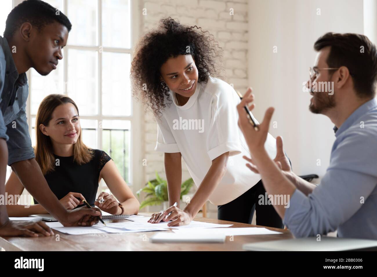 Diverse businesspeople listen team leader during meeting in boardroom ...