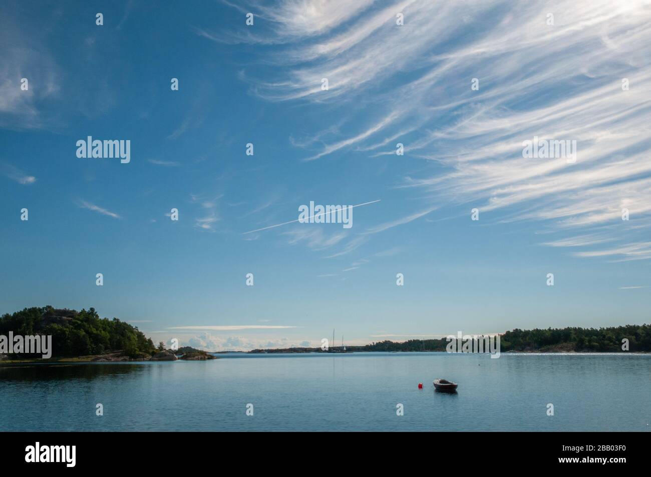 A quiet summer morning scene with a moored boat on still water among ...