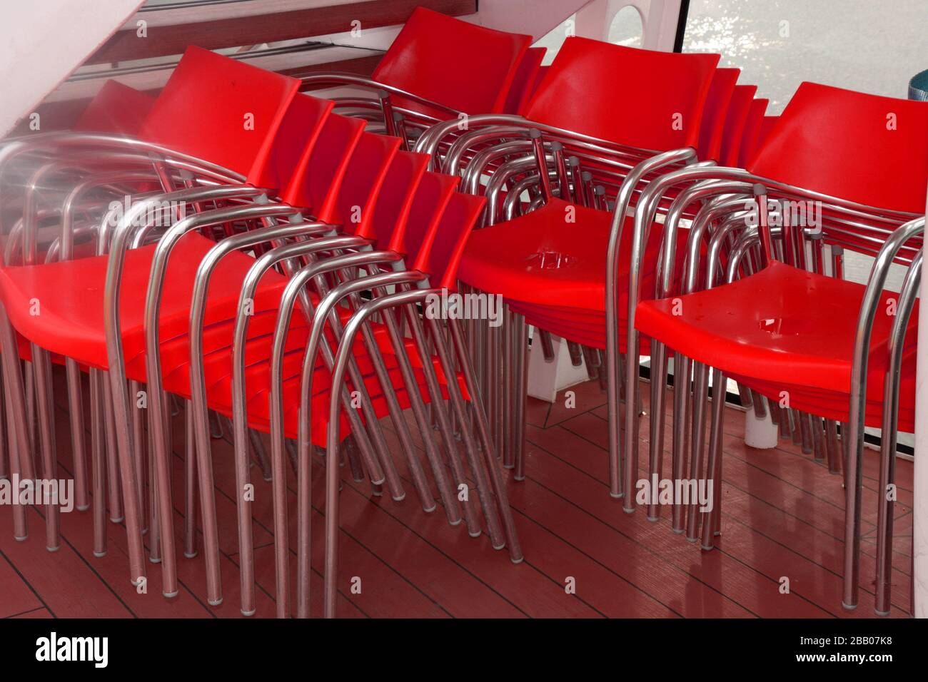 stacked red colored chairs in boat with light reflections, empty ...
