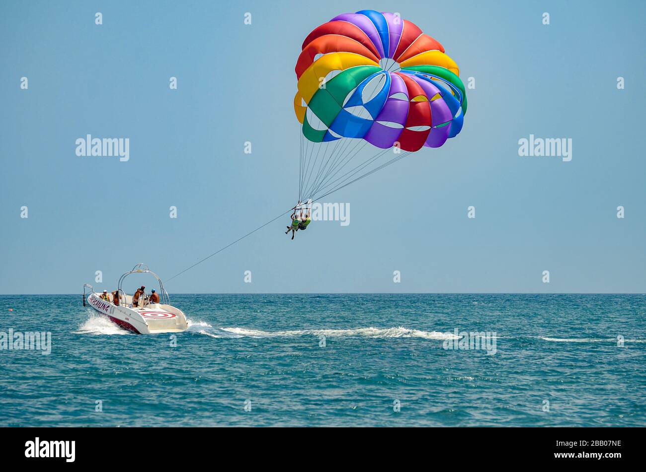 Holiday makers para sailing from power boat with colourful parachute ...