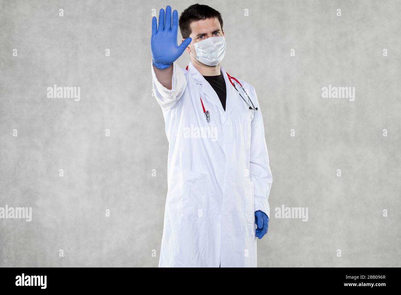 a doctor in protective clothing shows a stop sign with his hand Stock ...
