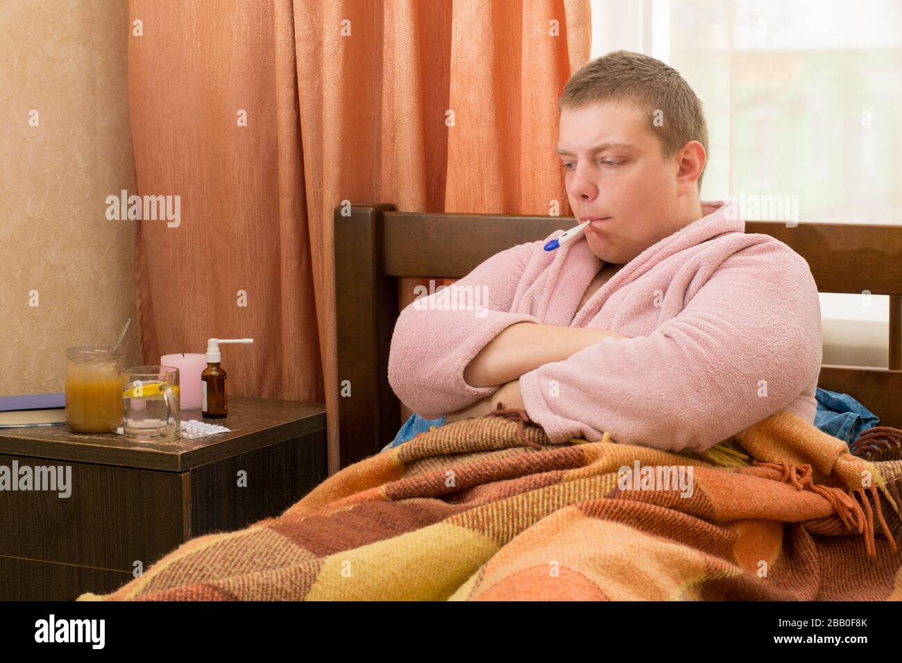 Sick guy with a thermometer in a bathrobe lying in the bed Stock Photo ...