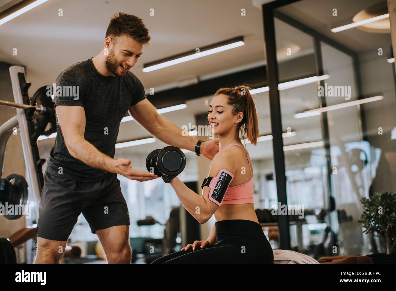 Attractive woman and a personal trainer with dumbbell weight training ...