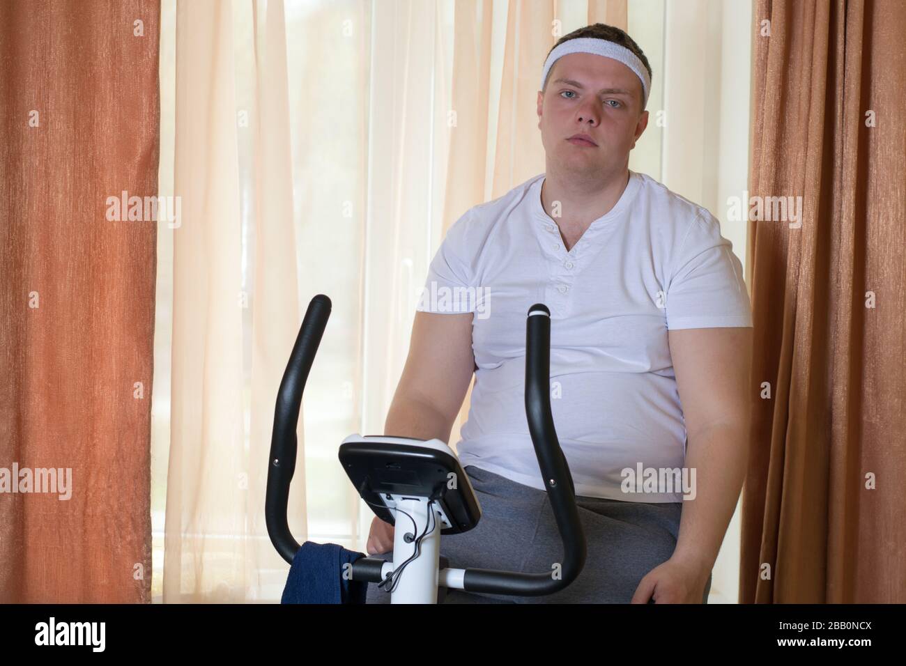 Fat guy exercising on stationary training bicycle at home Stock Photo ...