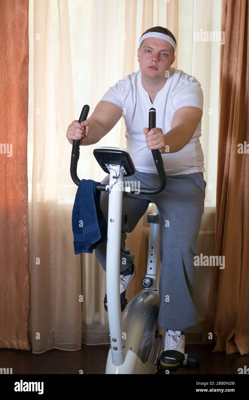 Fat guy exercising on stationary training bicycle at home Stock Photo ...