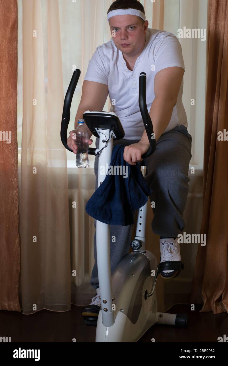 Fat guy exercising on stationary training bicycle at home Stock Photo ...