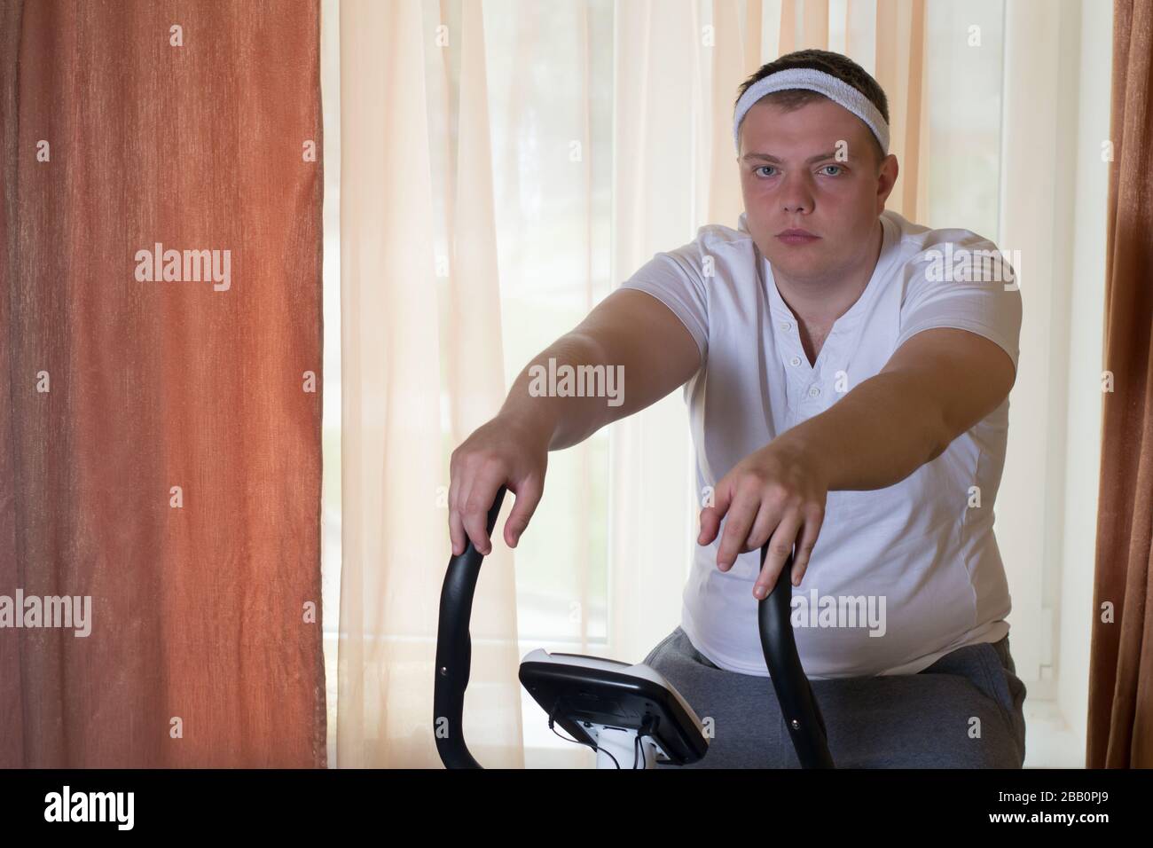 Fat guy exercising on stationary training bicycle at home Stock Photo ...