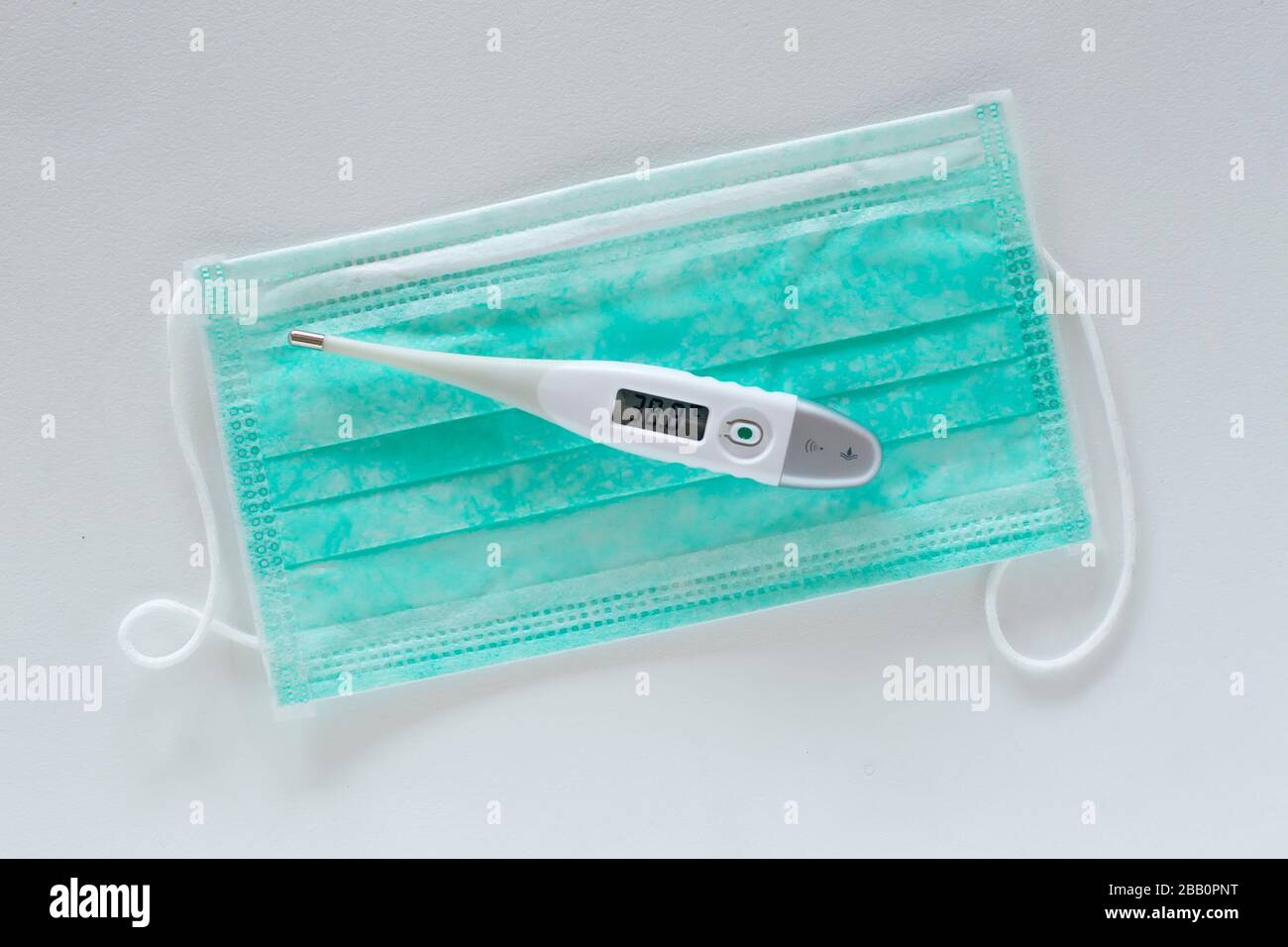 Surgical ear-loop mask and thermometer on the table Stock Photo - Alamy