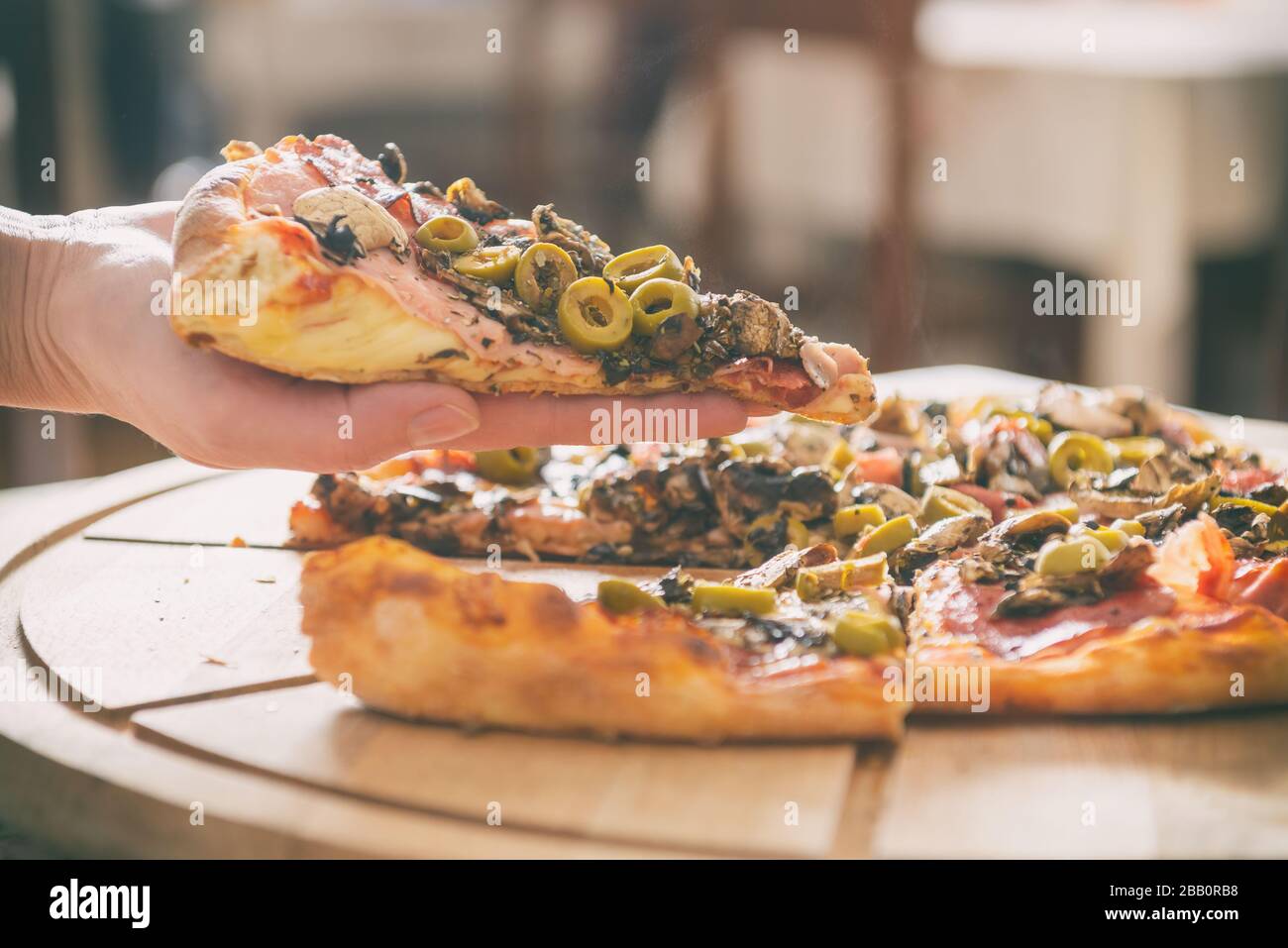 Hand holding piece of fresh original Italian pizza traditional in ...