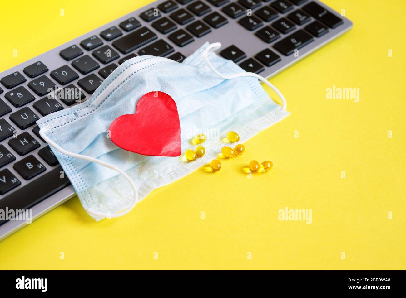 Blue cloth medical mask with heart and piils on computer keyboard. Home ...