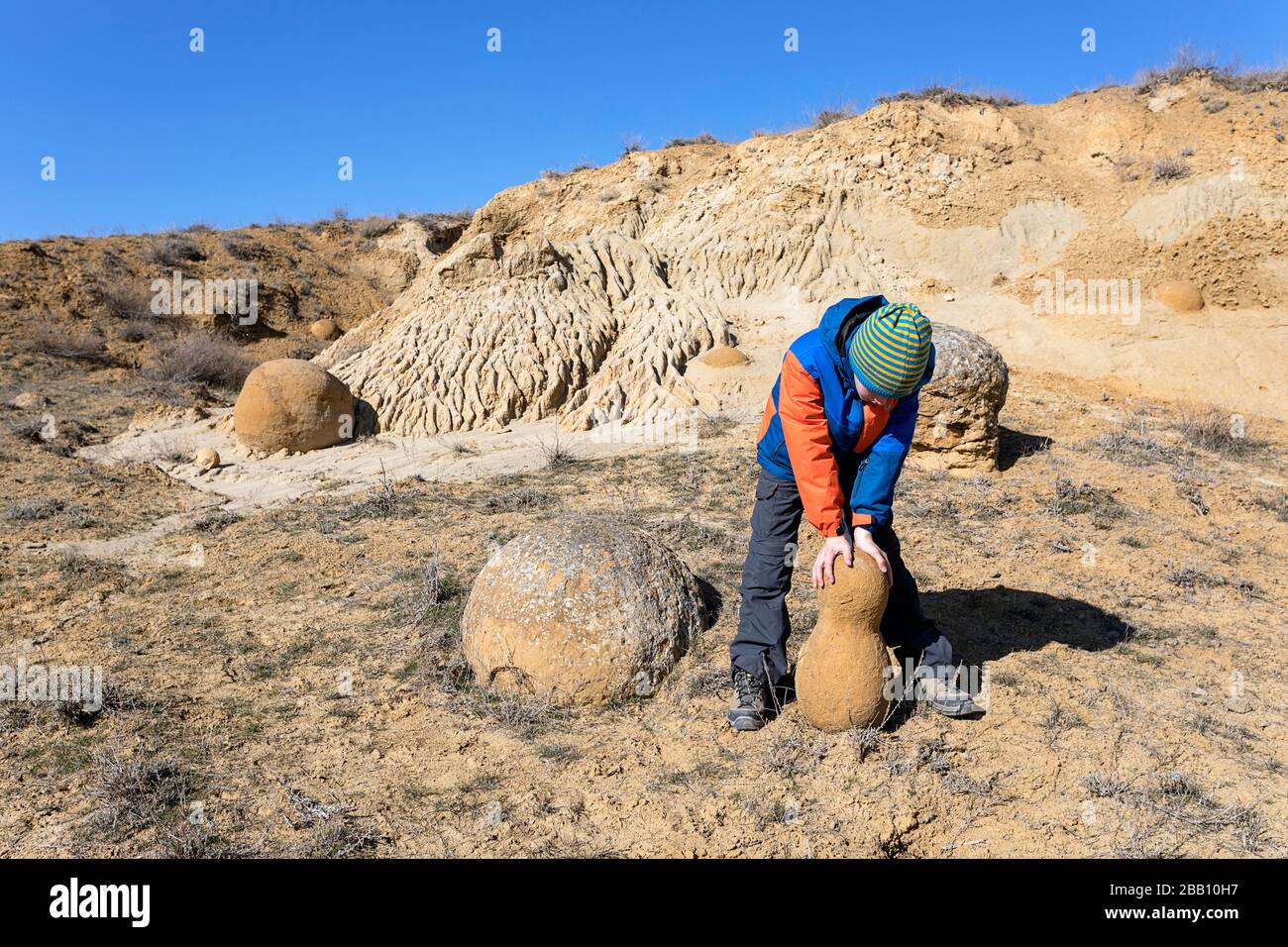 Young boy playing in valley of balls, round rocks in western Kazakhstan ...