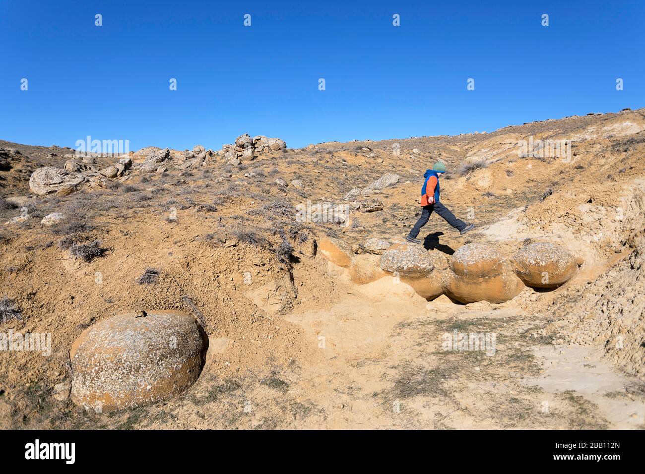 Young boy playing in valley of balls, round rocks in western Kazakhstan ...