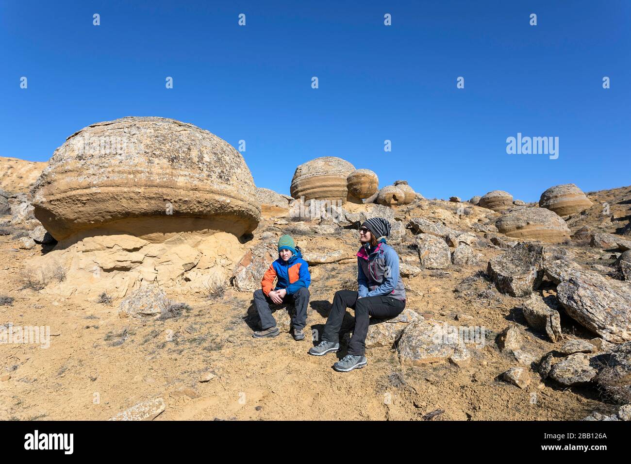 Mother and son sitting on round rocks in valley of balls, western ...