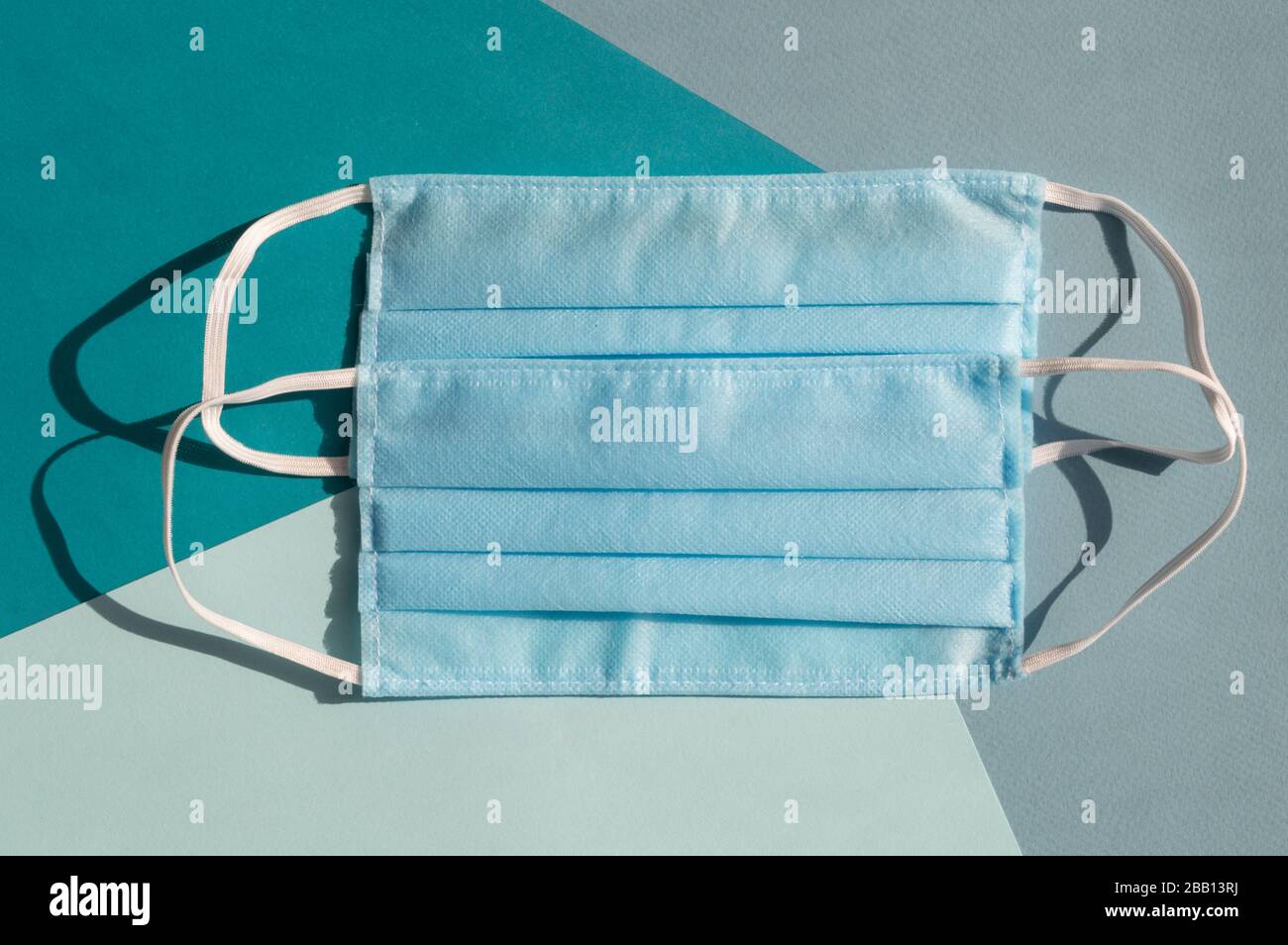 Two light blue medical disposable face masks on the mix of blue and ...