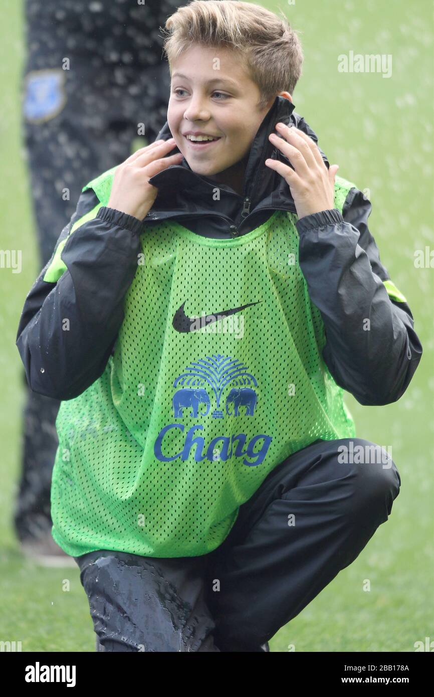 A young Everton ball boy is caught underneath the sprinklers before the ...