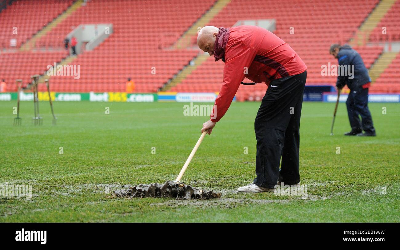 Groundstaff attempt to sweep the standing water off the pitch before ...