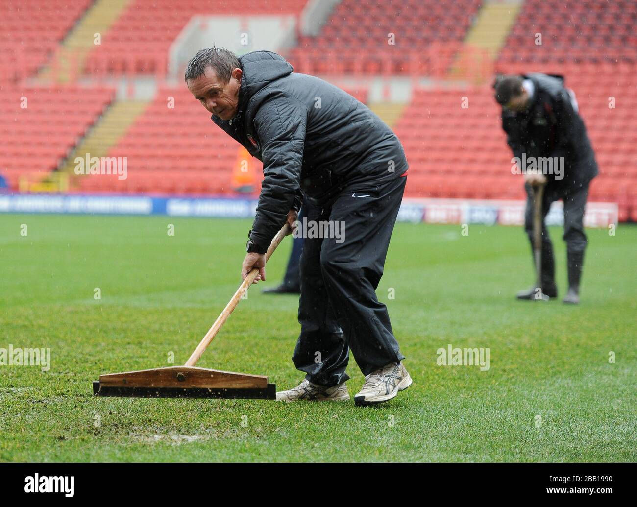 Groundstaff attempt to sweep the standing water off the pitch before ...