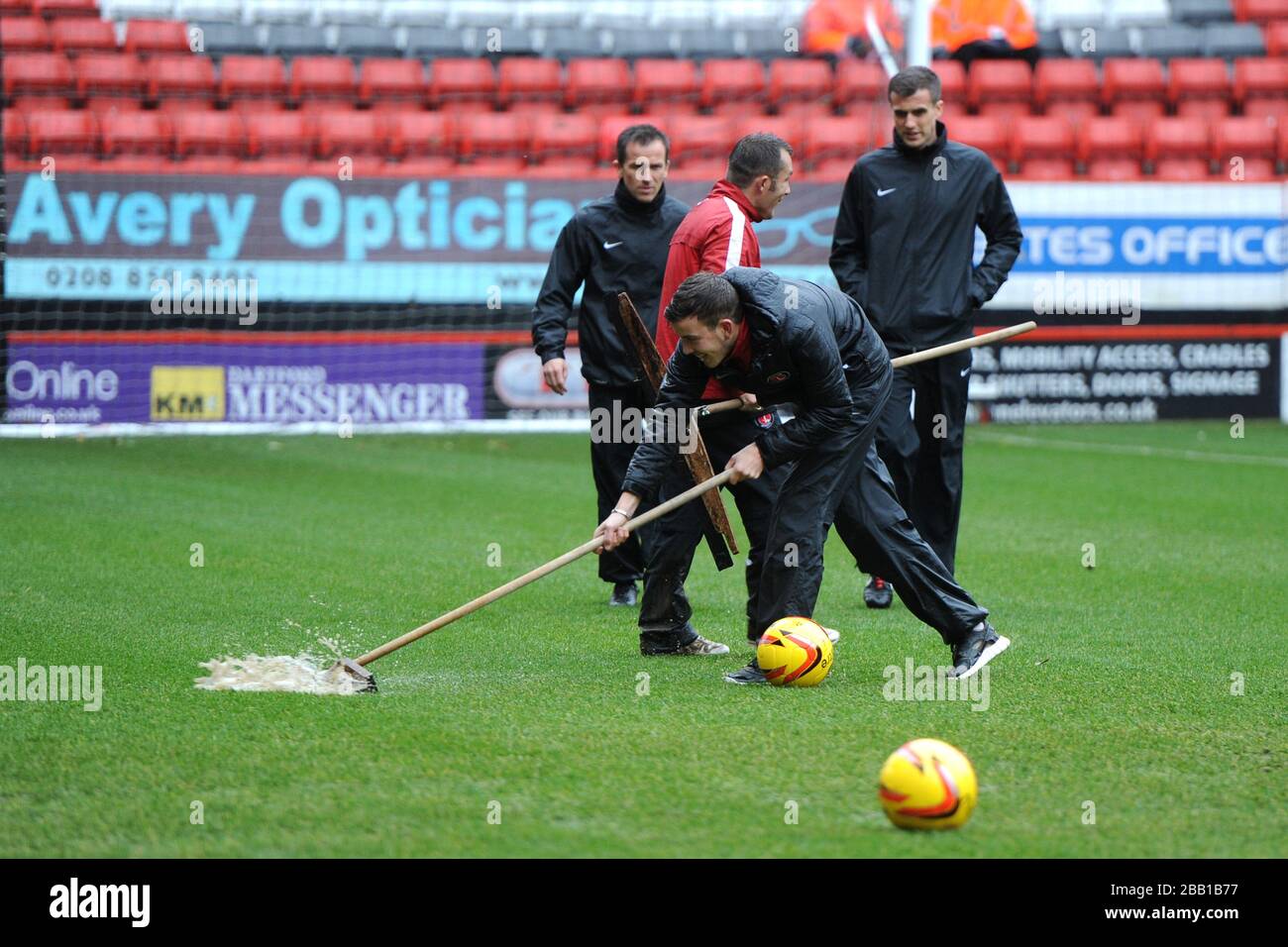 Groundstaff attempt to sweep the standing water off the pitch before ...