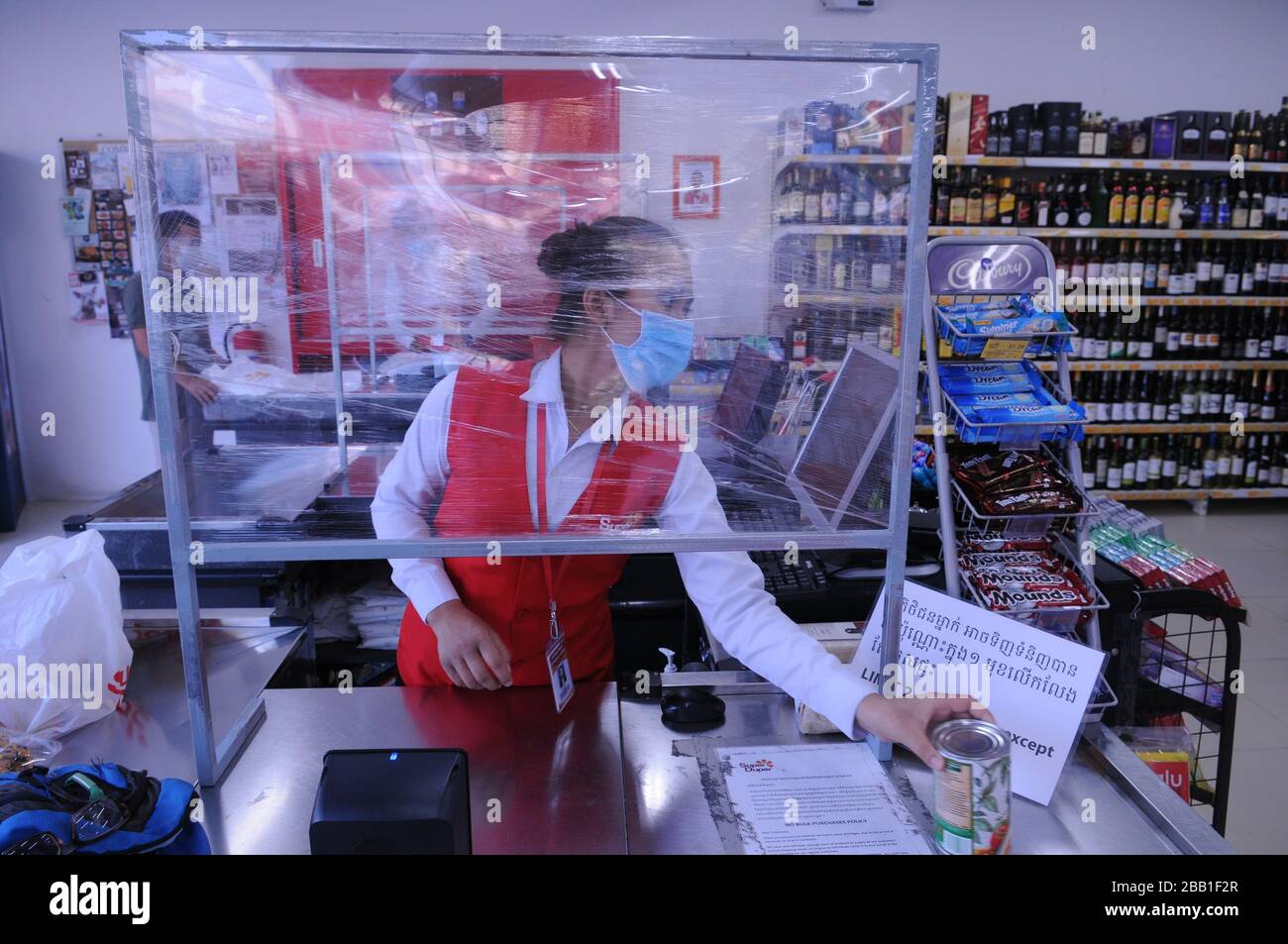 Supermarket cashier wears a protective face mask behind a homemade ...