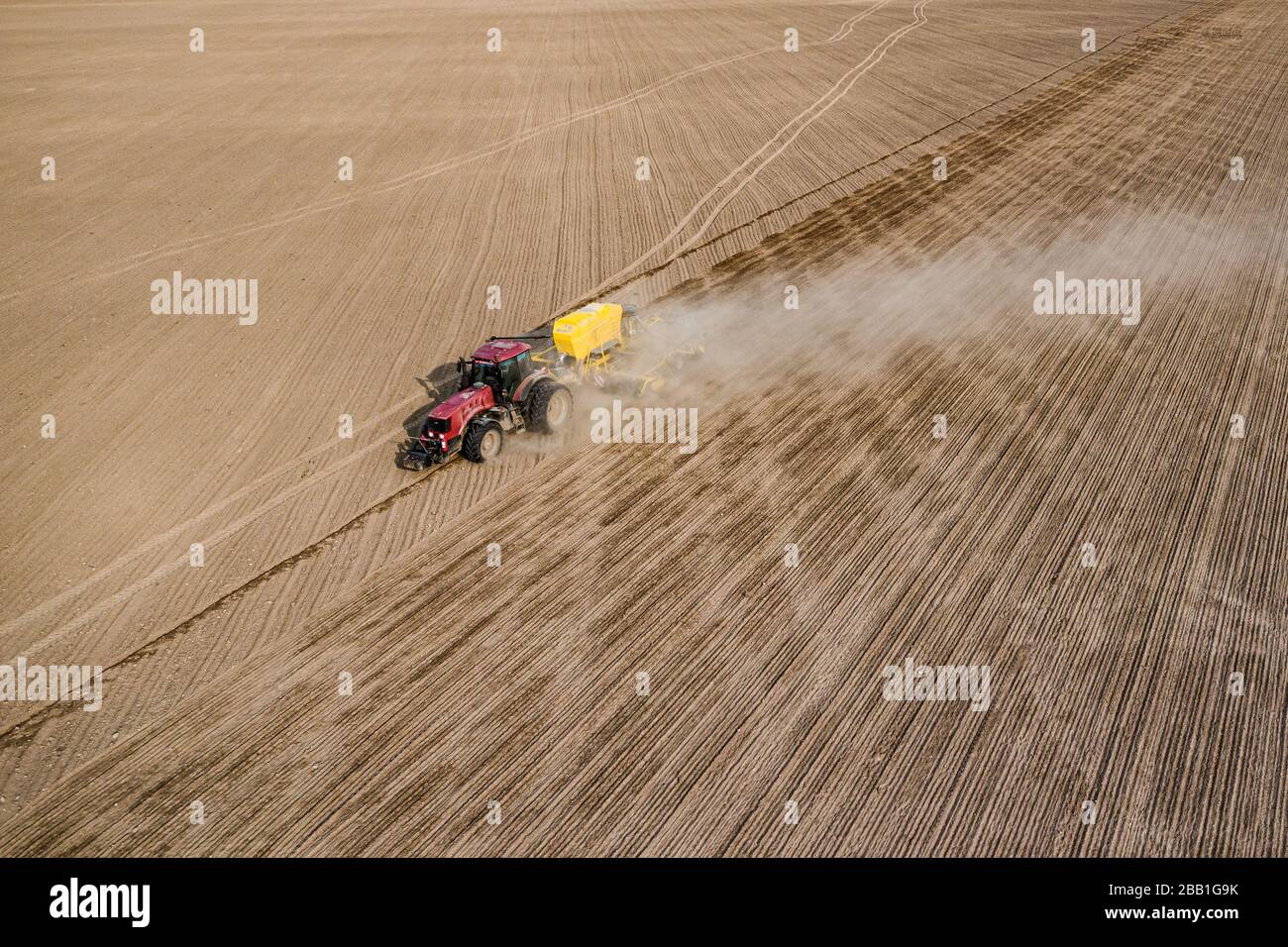 Aerial view of tractor with mounted seeder performing direct seeding of ...