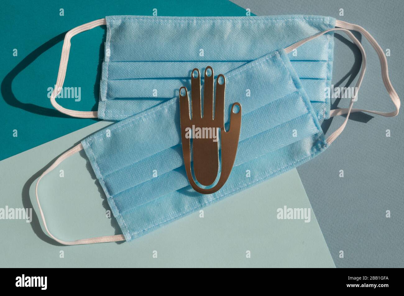 Metal hand on two light blue medical disposable face masks on the mix ...