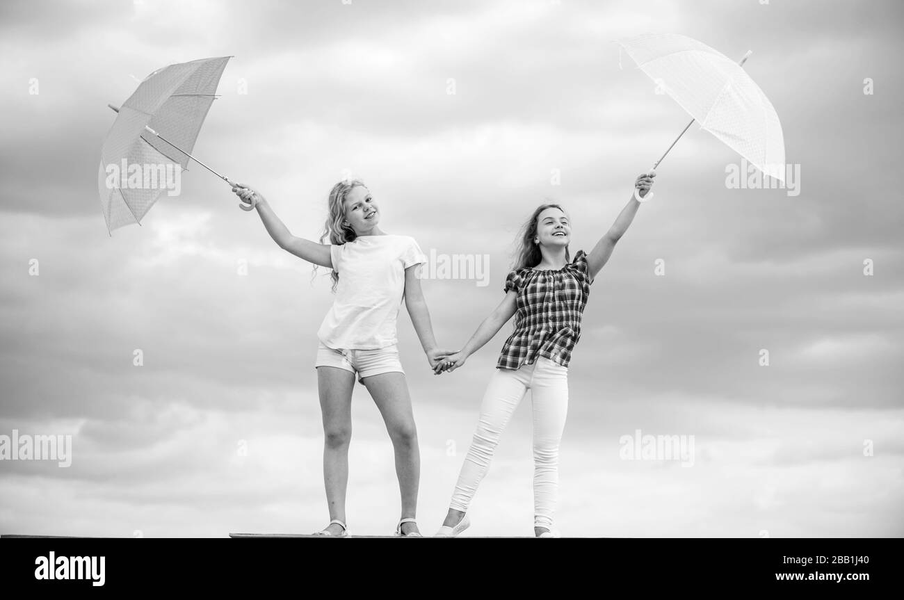 Weather changing. Girls friends with umbrellas cloudy sky background ...
