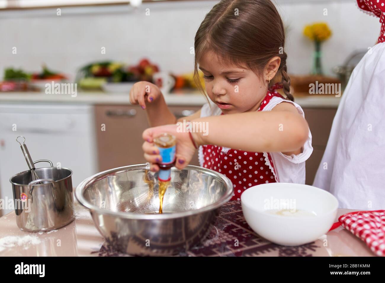 Little girl helping her mother cooking in the kitchen Stock Photo - Alamy