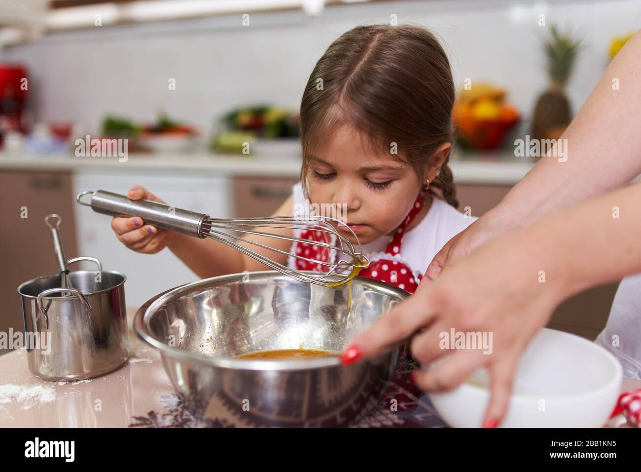 Little girl helping her mother cooking in the kitchen Stock Photo - Alamy