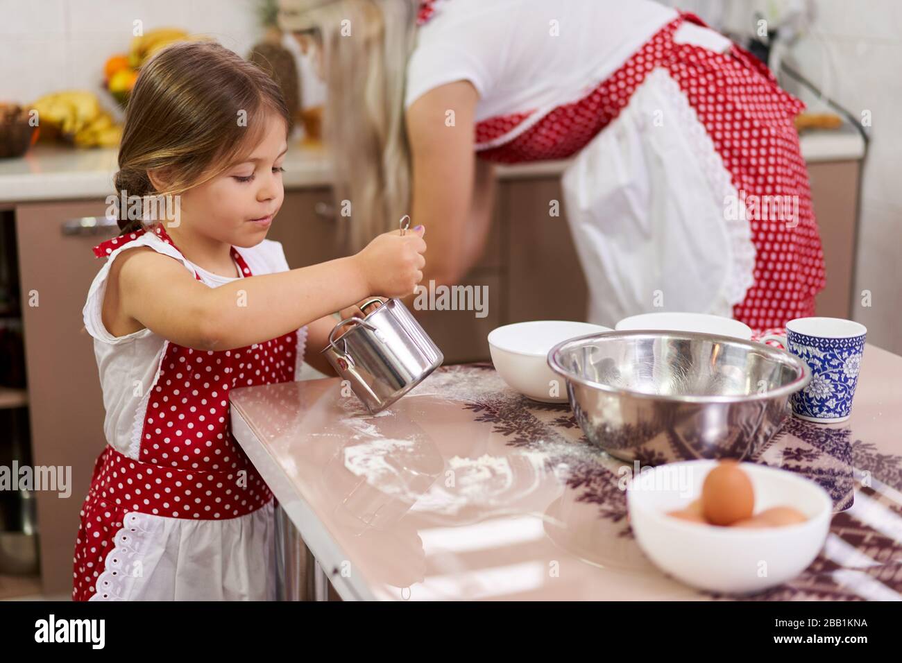 Little girl helping her mother cooking in the kitchen Stock Photo - Alamy
