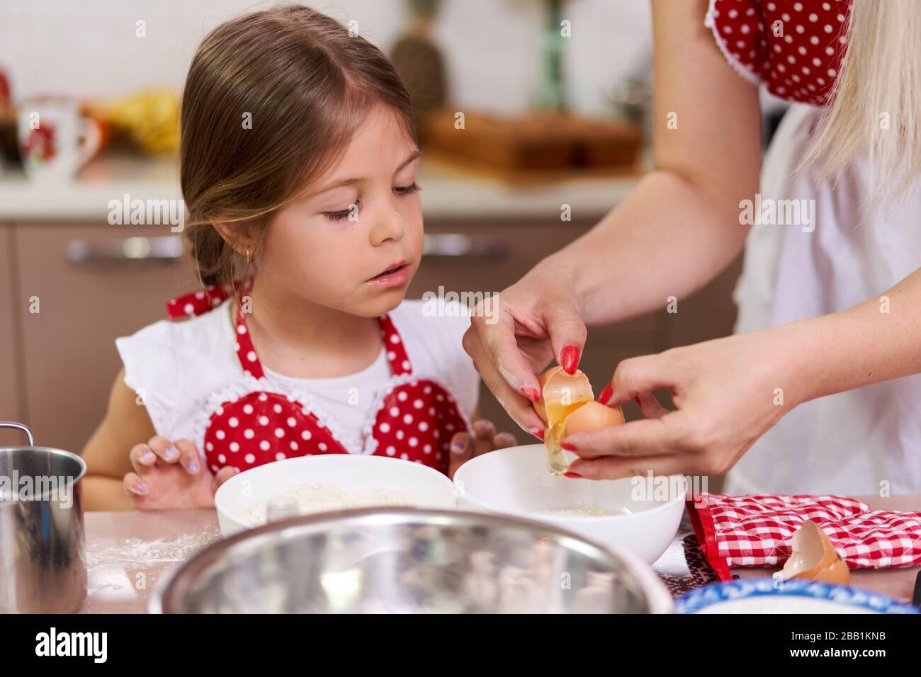 Little girl helping her mother cooking in the kitchen Stock Photo - Alamy