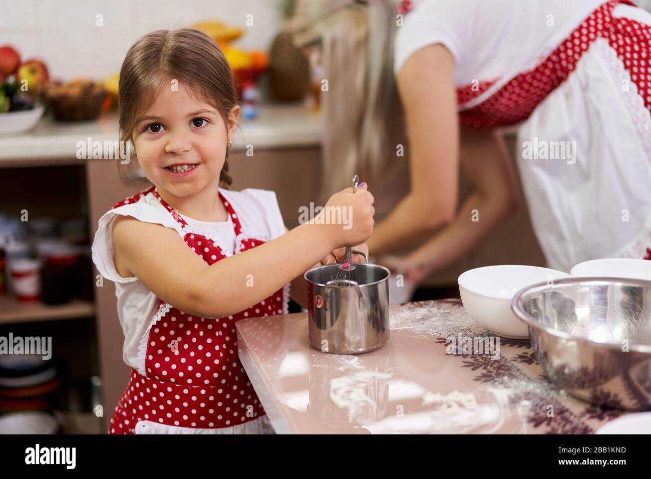 Little girl helping her mother cooking in the kitchen Stock Photo - Alamy