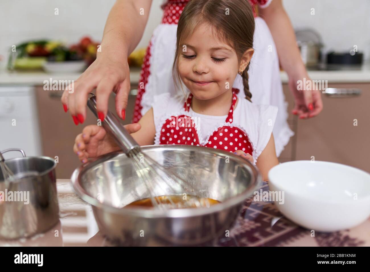 Little girl helping her mother cooking in the kitchen Stock Photo - Alamy