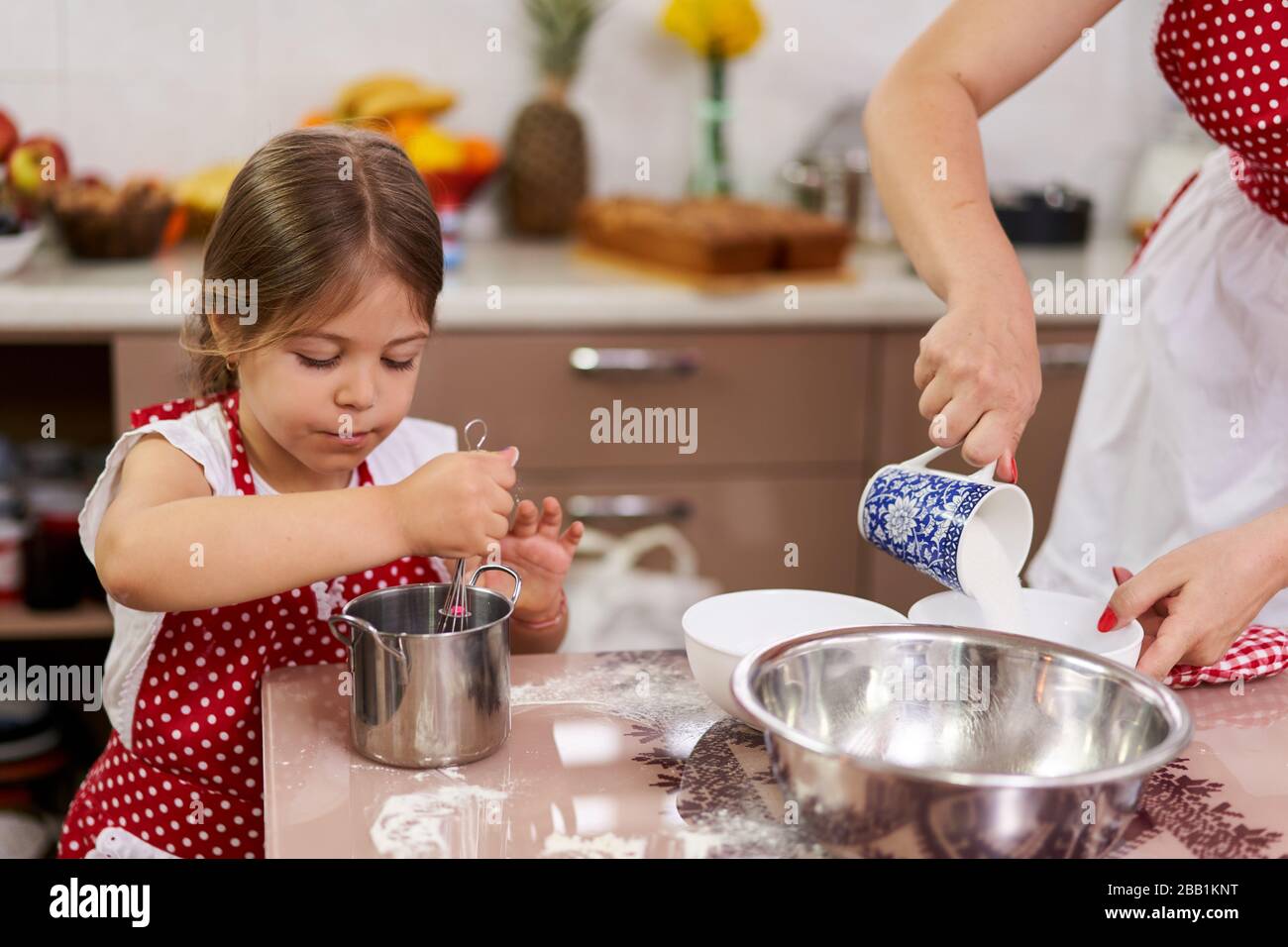 Little girl helping her mother cooking in the kitchen Stock Photo - Alamy